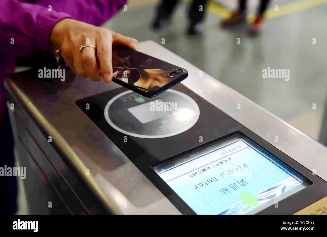 A passenger puts her smartphone above a turnstile to have the QR code ...
