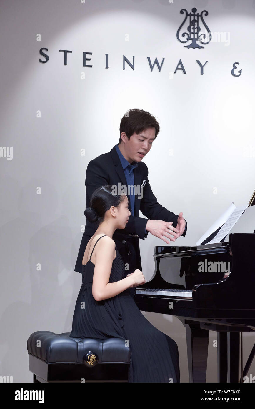 Chinese pianist Li Yundi instructs an enthusiast to play the piano at ...