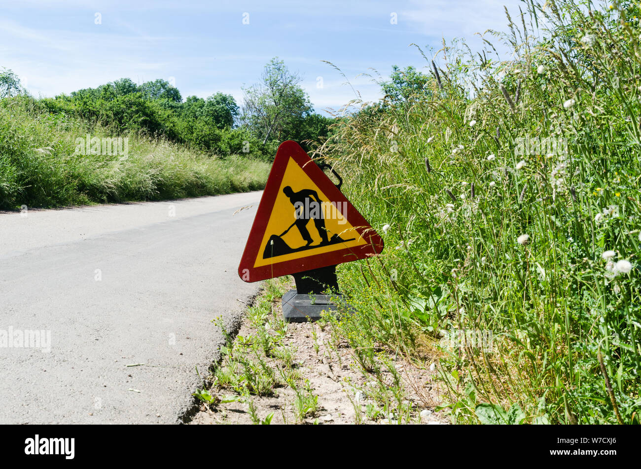 Roadwork sign by roadside in a lush greenery in summer season Stock ...