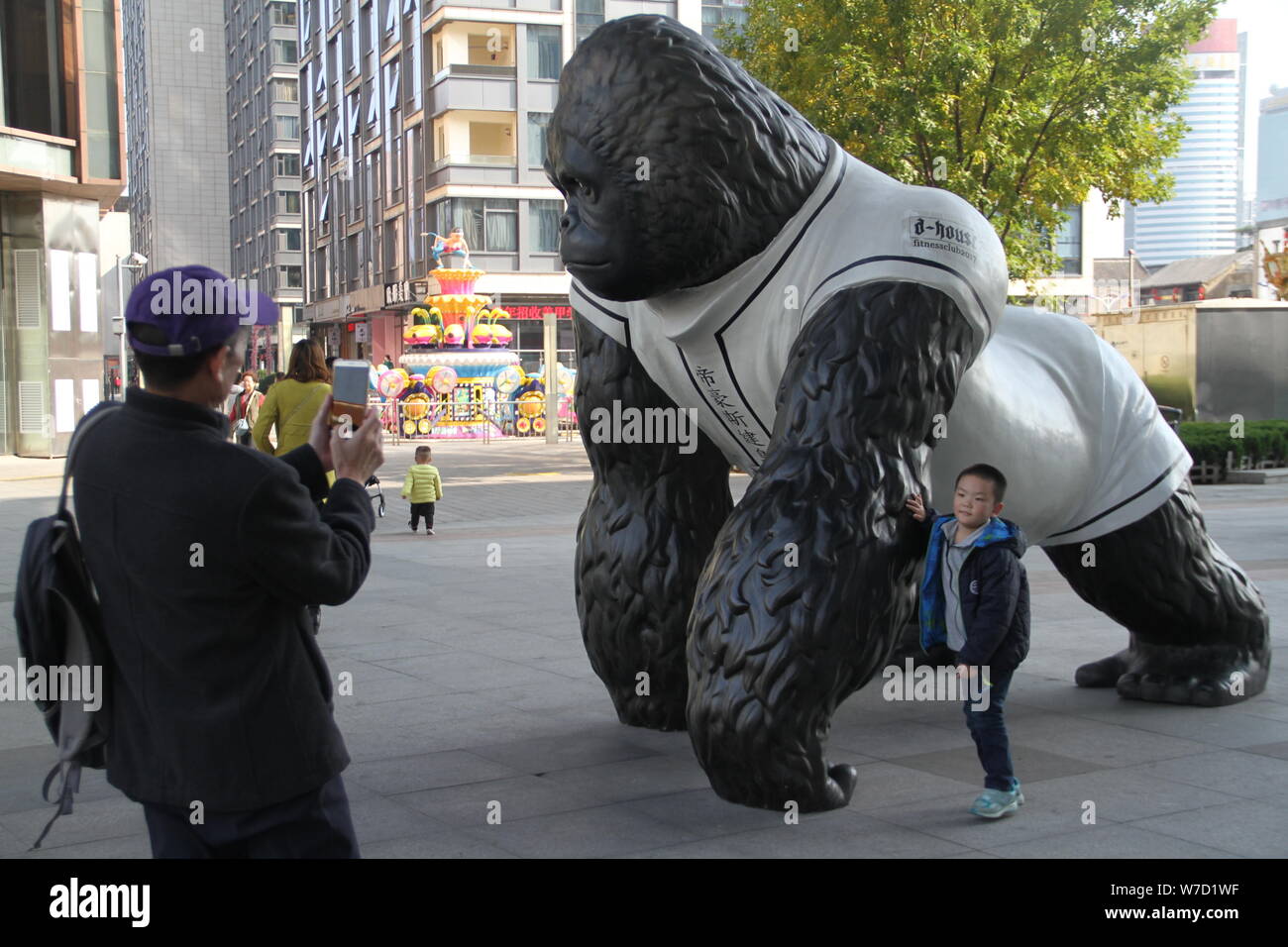 A child takes photos with a gorilla sculpture on the street in Ji'nan ...