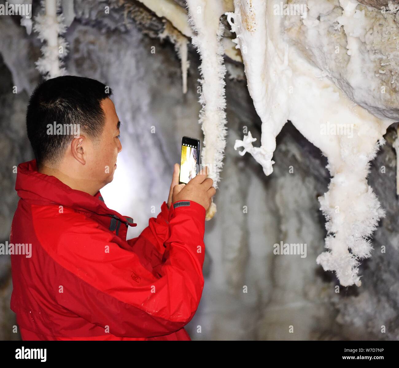 A visitor takes photos of the snow-white stalactites and stalagmites in ...