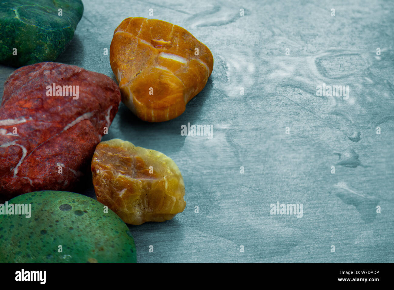 Colored stones close up image on surface with water drops. Abstract ...