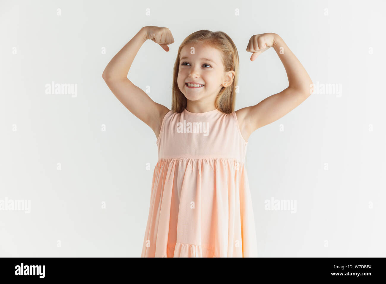 Stylish little smiling girl posing in dress isolated on white studio ...