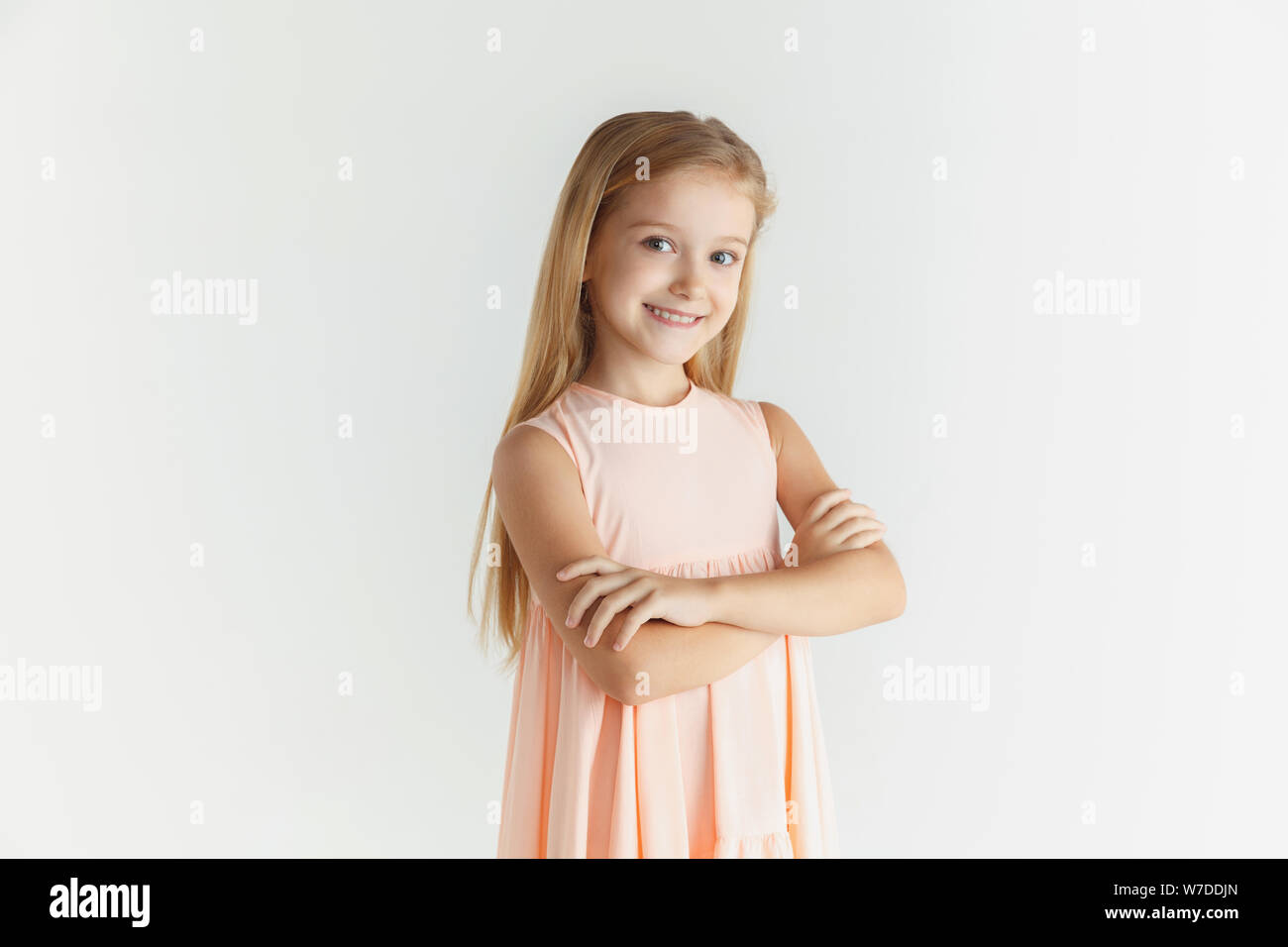 Stylish little smiling girl posing in dress isolated on white studio ...