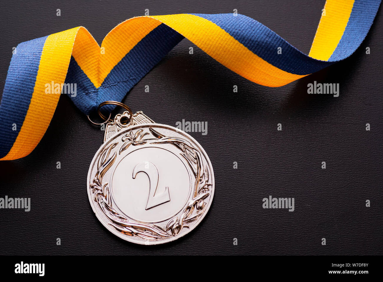 Second place runner-up silver medal on a twirled blue and gold ribbon ...