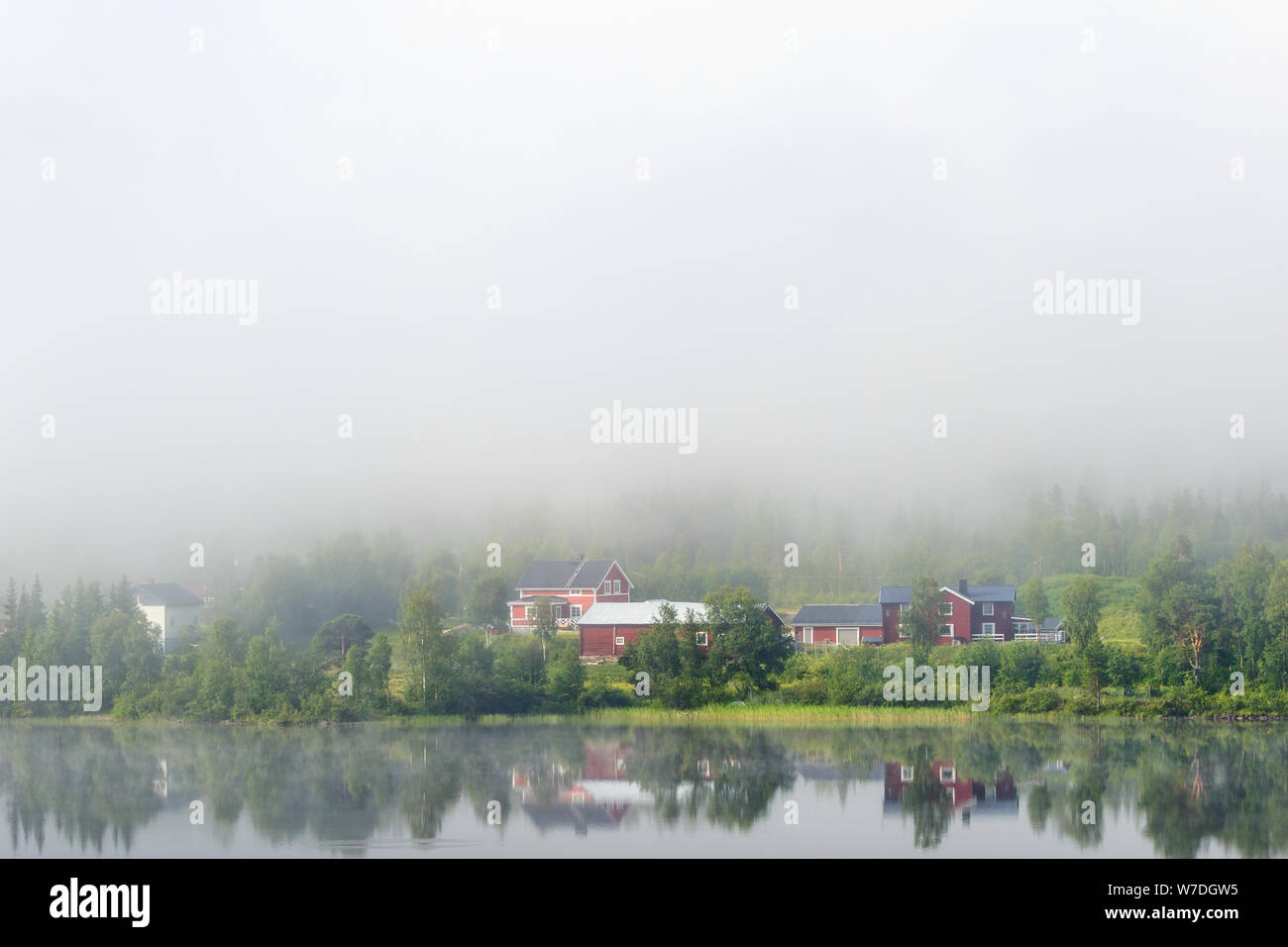Farm at a mirrored lake and fog in a forest landscape Stock Photo - Alamy