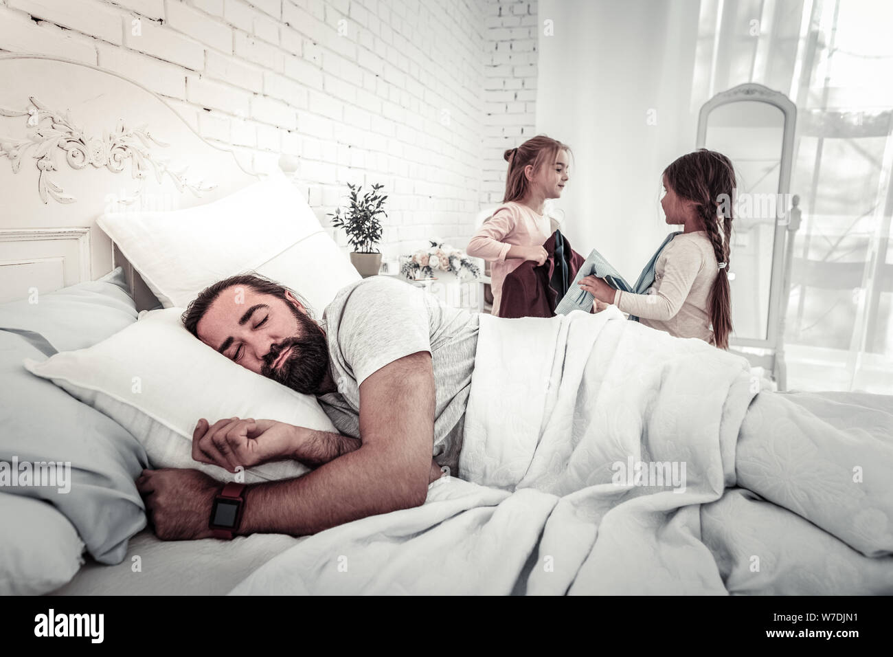 Sleeping dad with his two kids in background about to wake him up Stock ...
