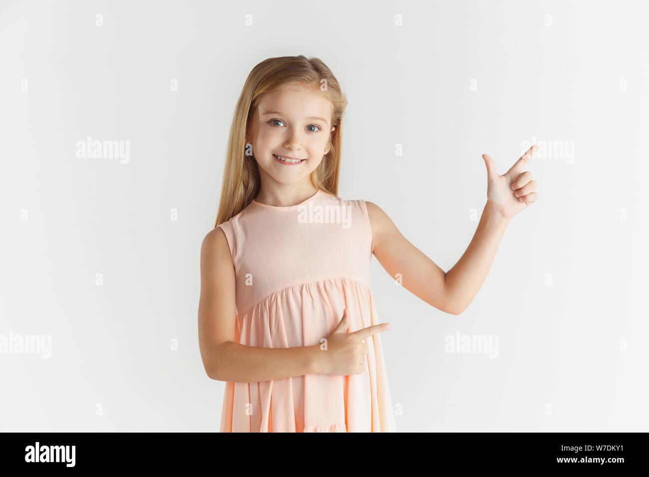 Stylish little smiling girl posing in dress isolated on white studio ...