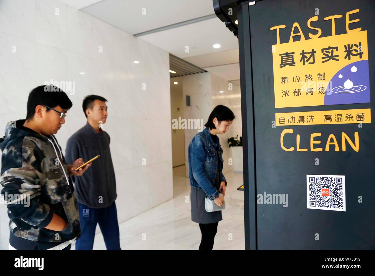 Customers wait to buy noodles in front of a mobile self-service noodle ...