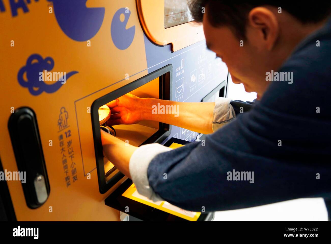 A customer gets his noodles from a mobile self-service noodle vending ...