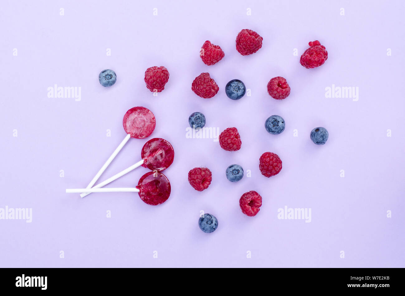 Three Red Lollipops, Blueberries and Raspberries on a Violet Color ...