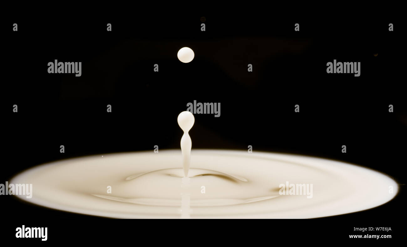 Drop of milk - milk droplet falling on white liquid and creating splash ...