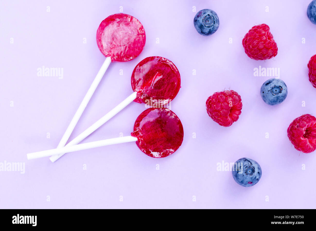 Three Red Lollipops, Blueberries and Raspberries on a Violet Color ...
