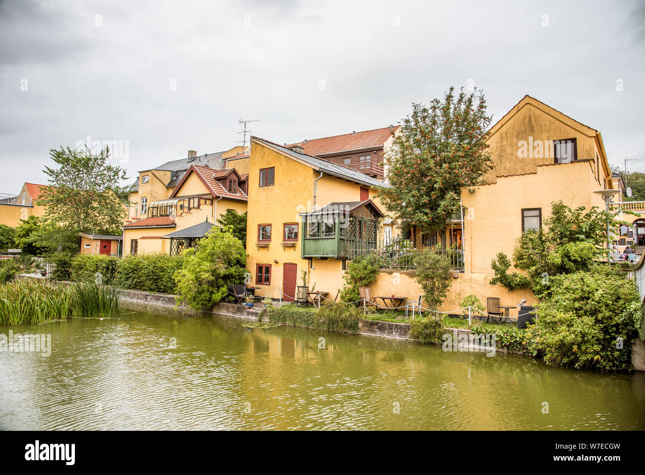 a picturesque canal along old yellow houses at Frederiksvaerk, Denmark ...