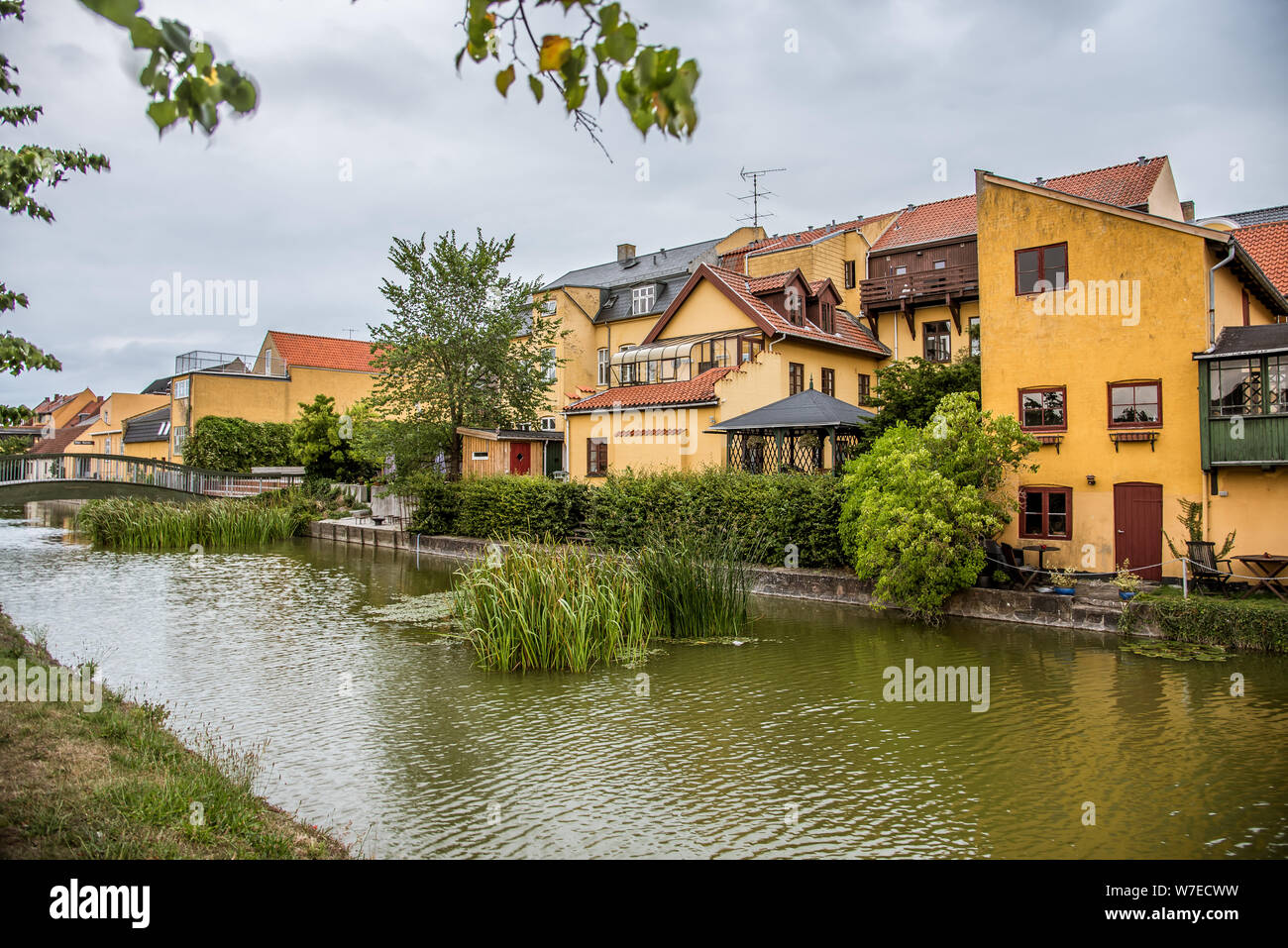 a picturesque canal along old yellow houses at Frederiksvaerk, Denmark ...