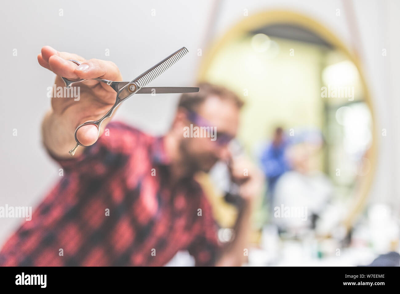 Modern man hairdresser holding sharp professional scissors and using ...