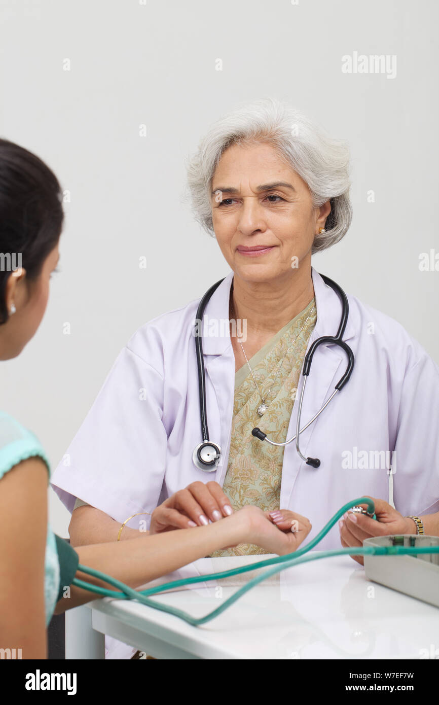 Female doctor checking patient blood pressure Stock Photo - Alamy