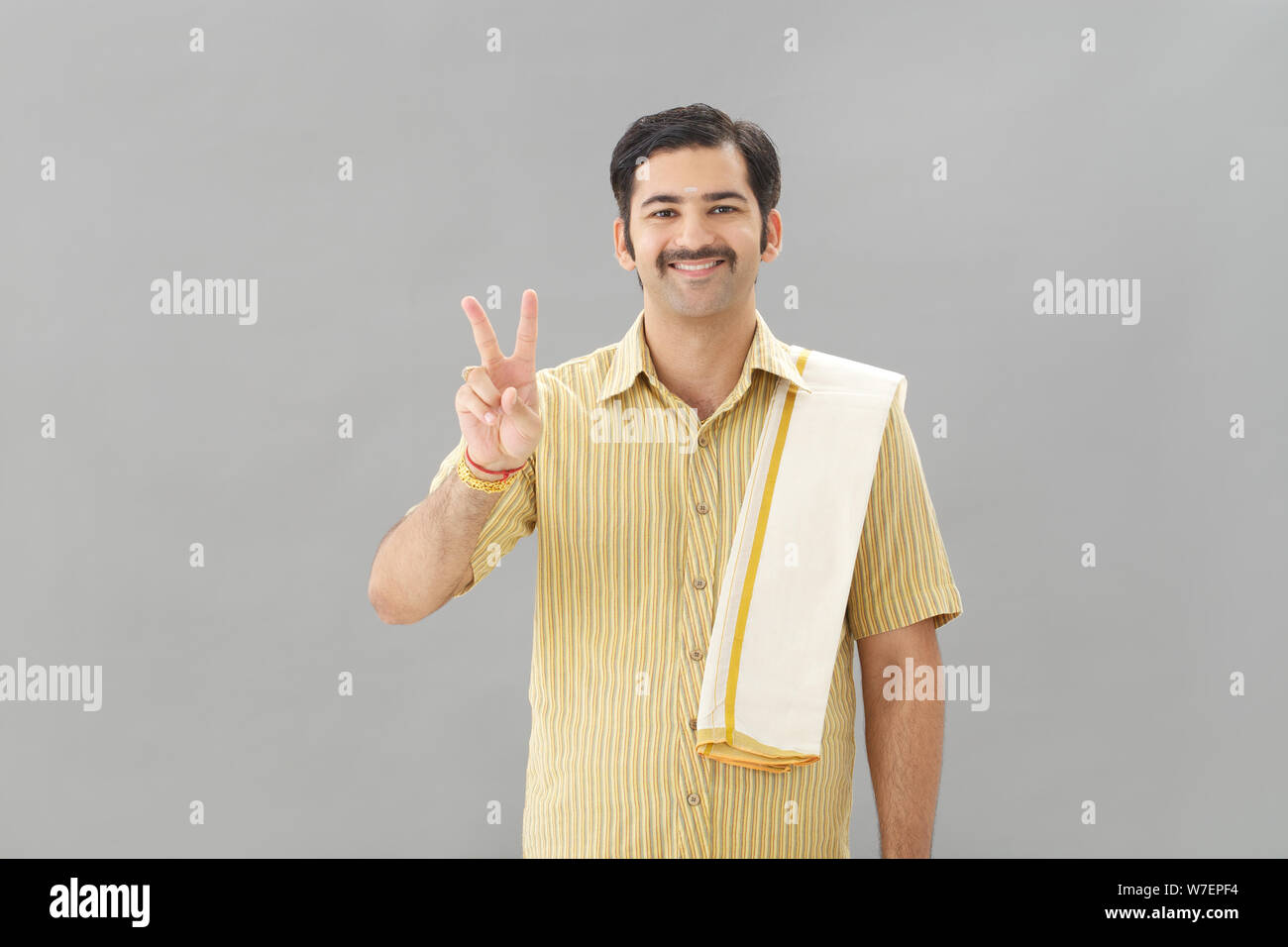 South Indian man showing v sign and smiling Stock Photo - Alamy
