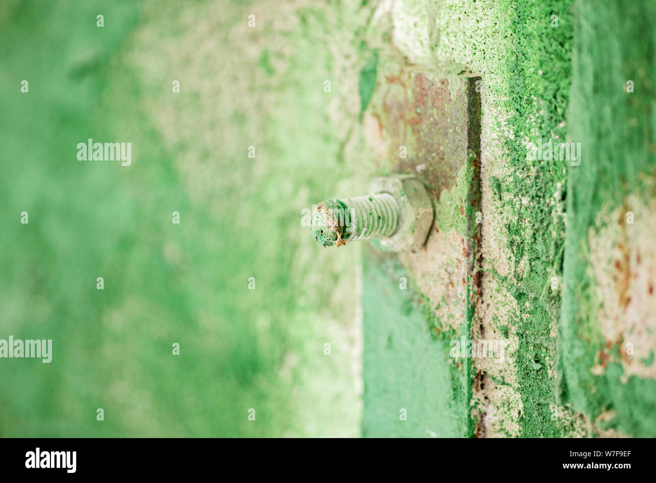 Old painted bolt and nut in a concrete green wall. metal mount to the ...