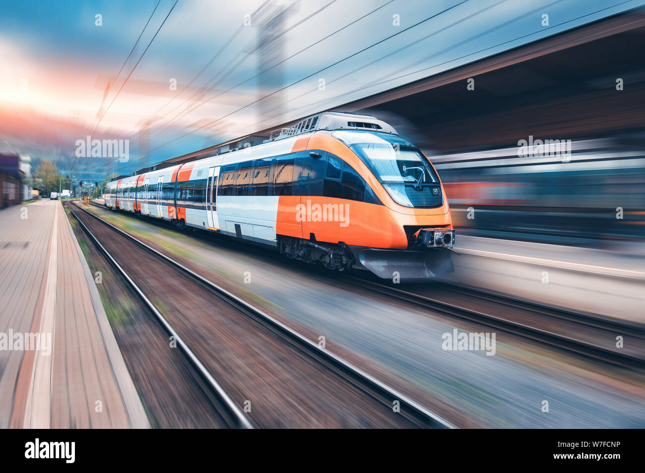 High speed orange train in motion on the railway station Stock Photo ...