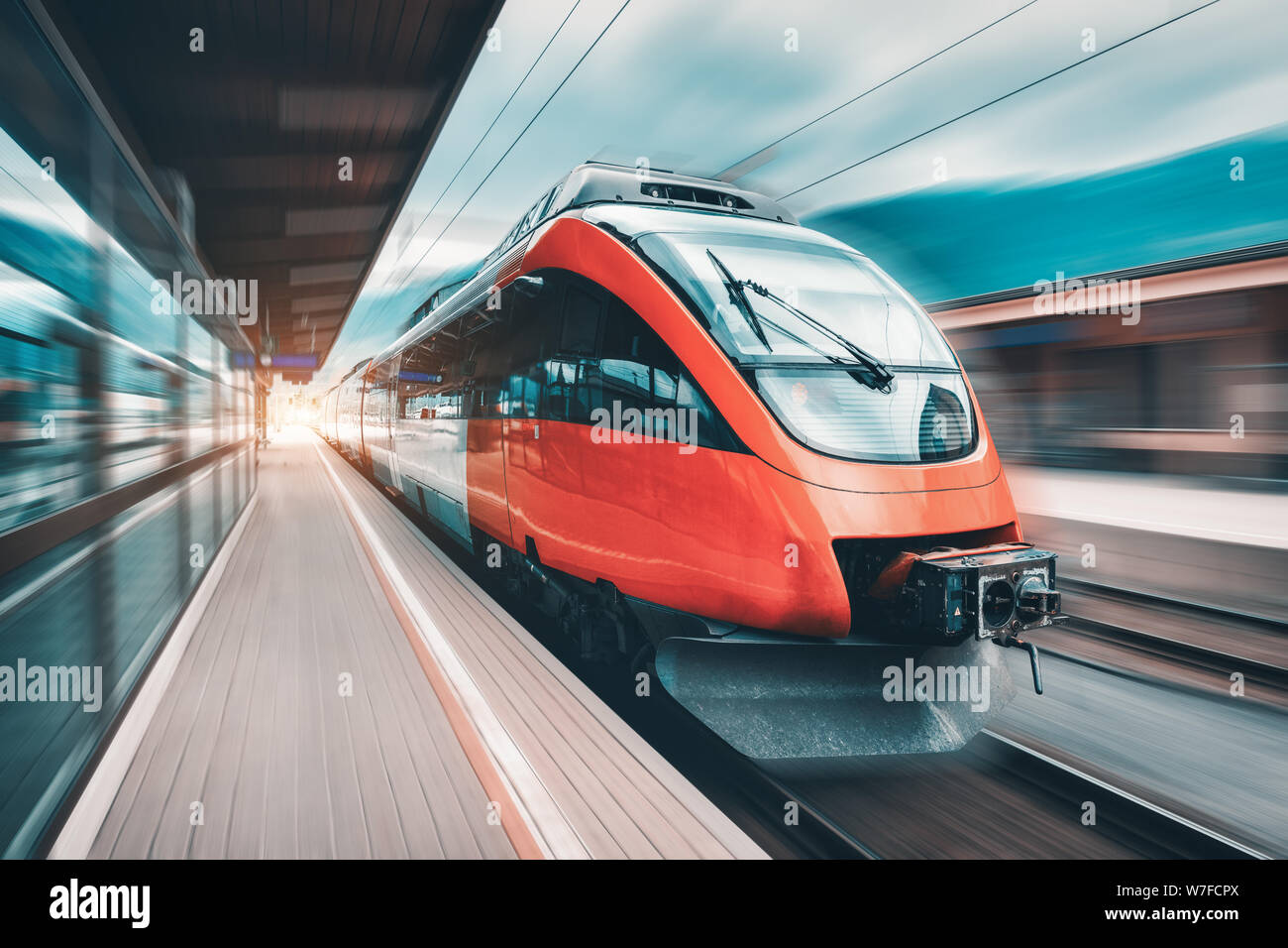 High speed orange train in motion on the railway station Stock Photo ...