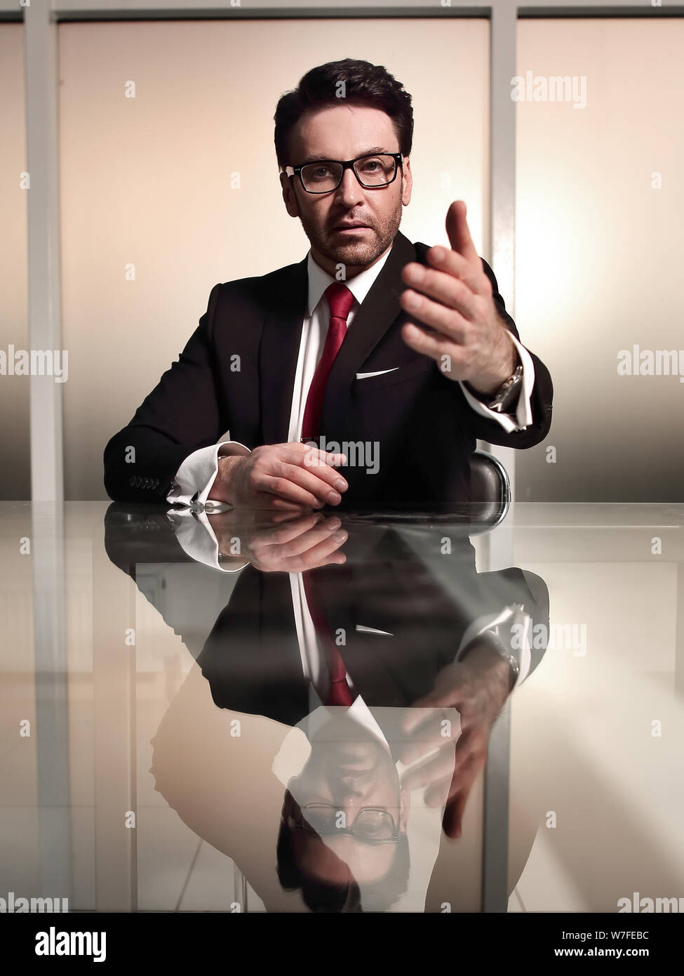 businessman sitting at his Desk and holding out his hand for a ...