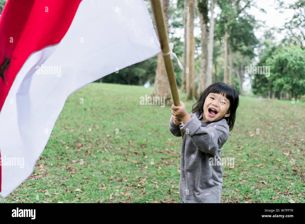 Indonesian girl holding bamboo stick with big flag Stock Photo - Alamy