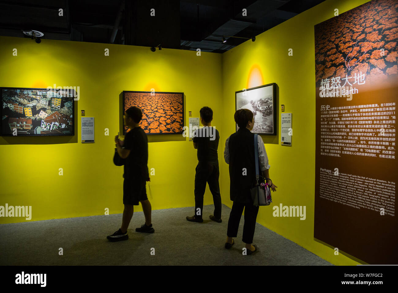 Visitors look at the photos displayed at the National Geographic ...