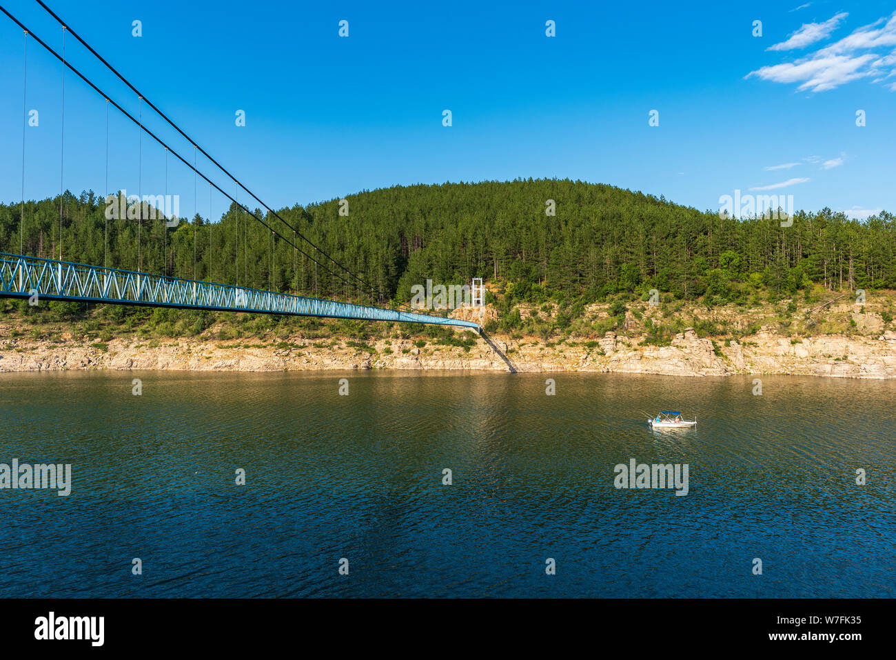Fisherman boat crossing river under suspension bridge Stock Photo - Alamy