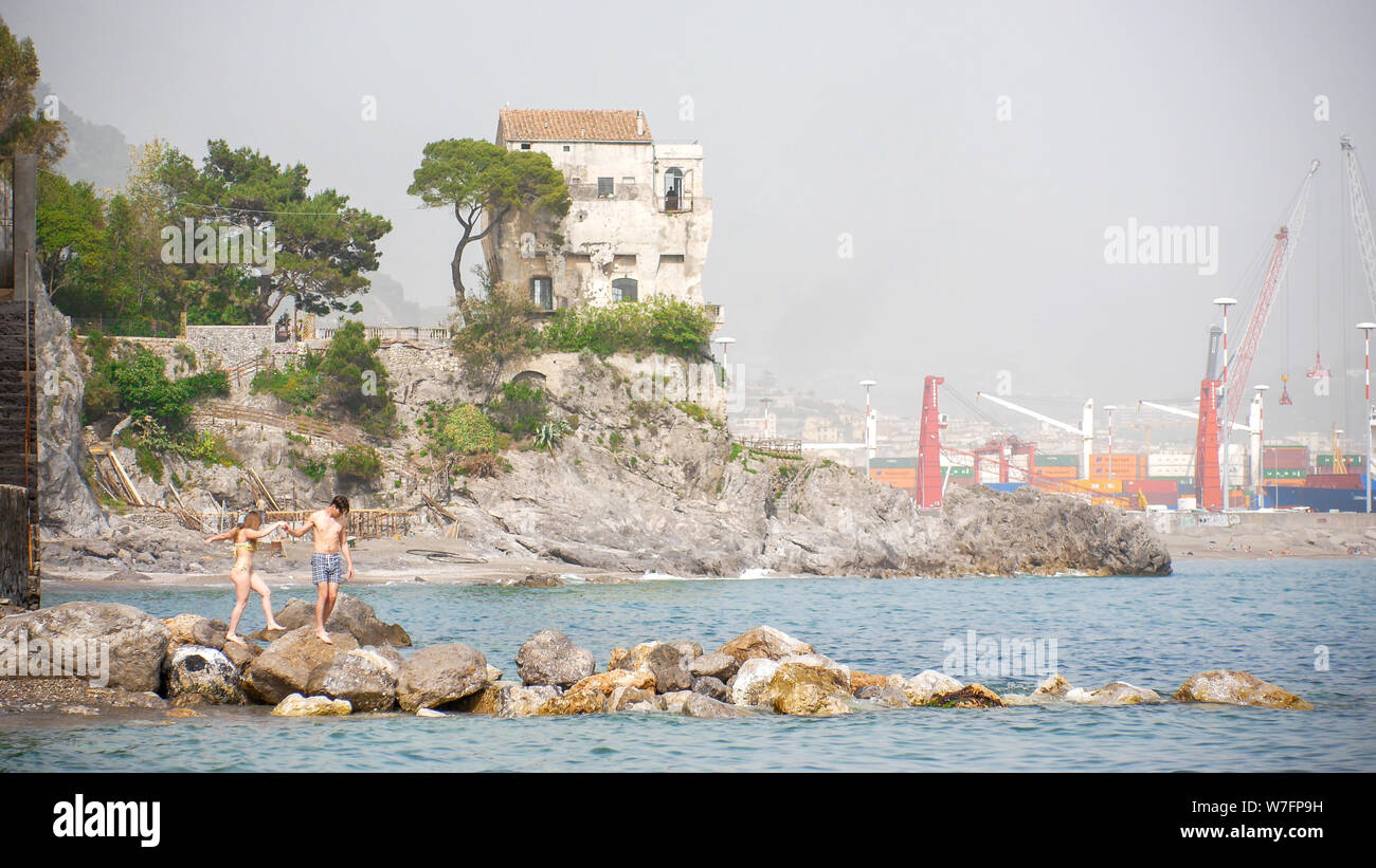 Young woman and man walk along the stones in the water and hanging ...