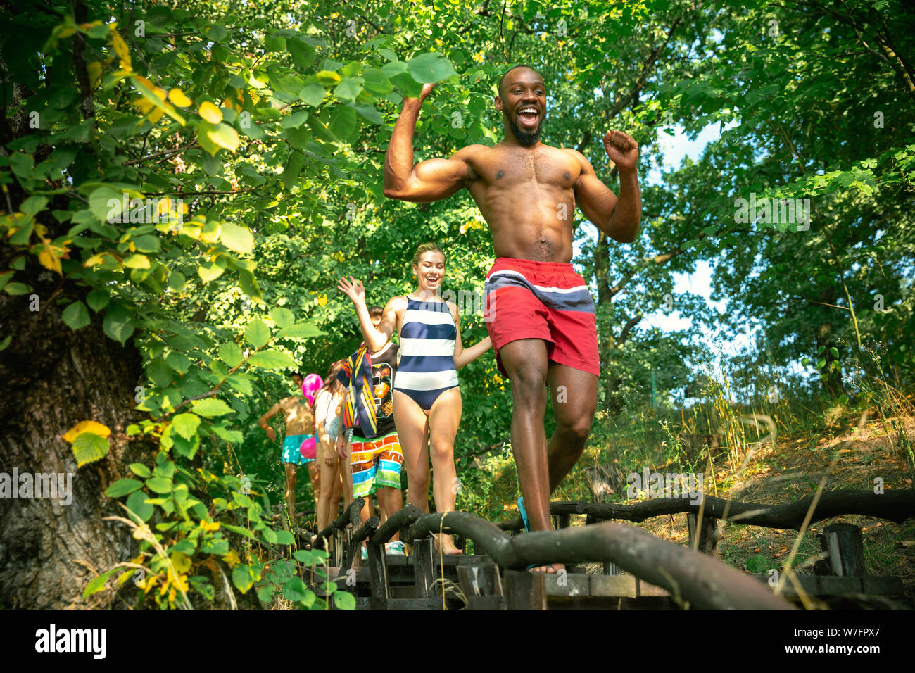 Group of happy friends having fun while running to swim on river ...