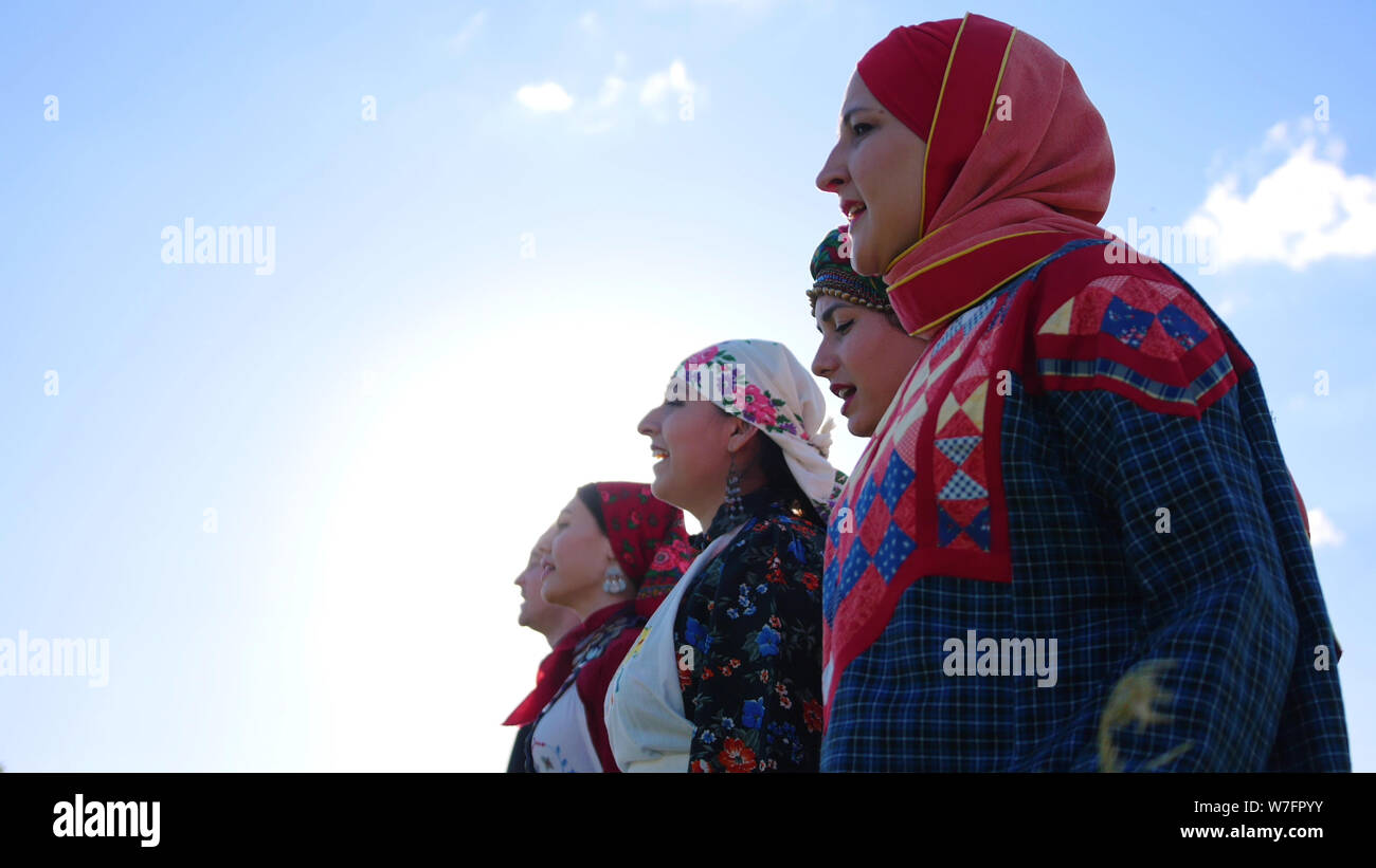People in traditional russian clothes walking in a row on the field and ...