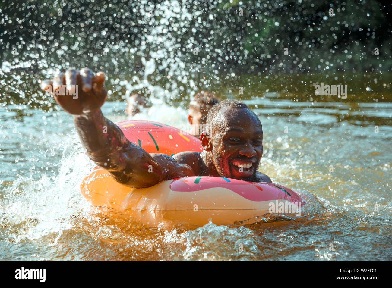 Happy man having fun while laughting and swimming in river. Joyful male ...