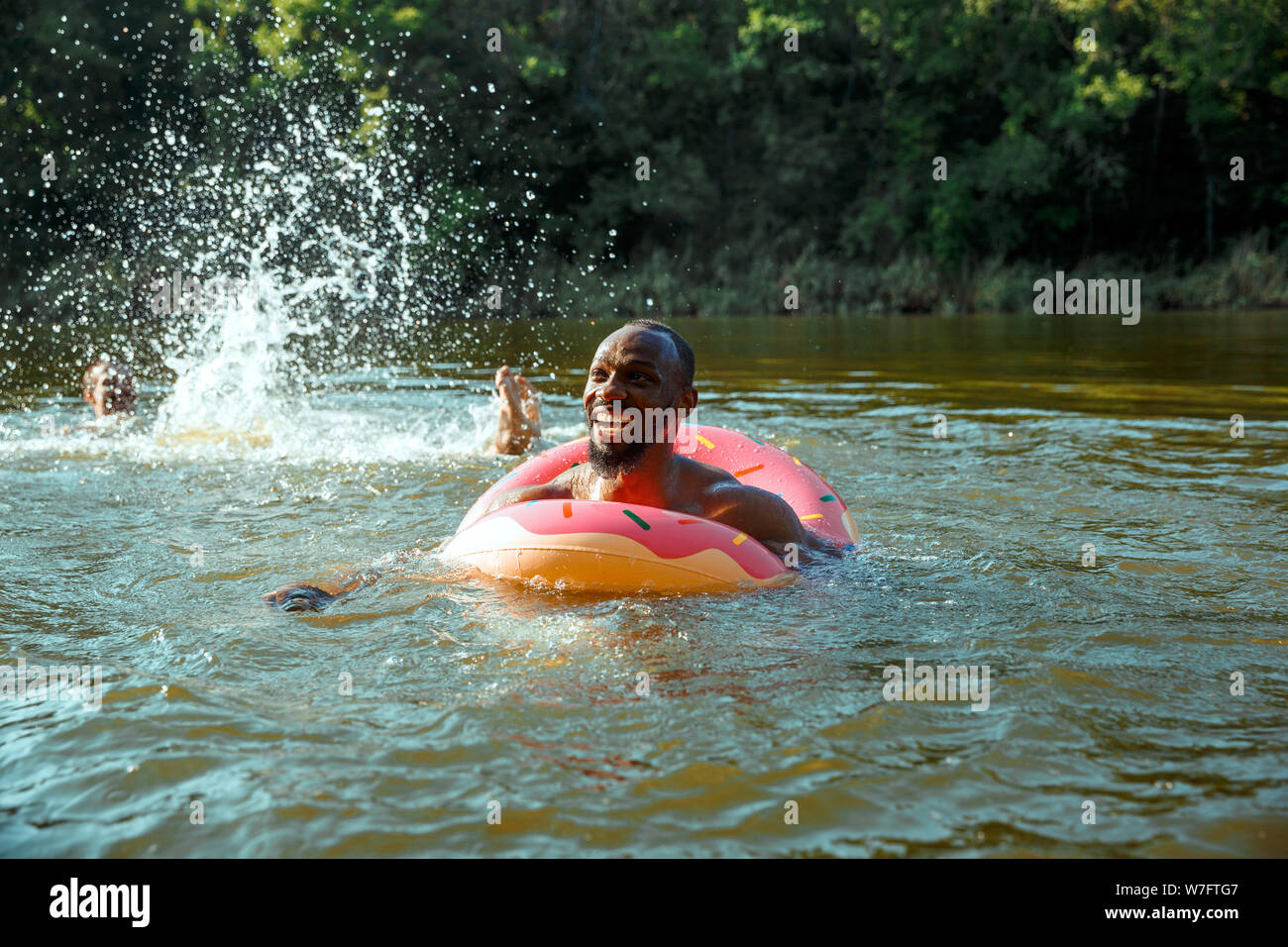 Happy man having fun while laughting and swimming in river. Joyful male ...