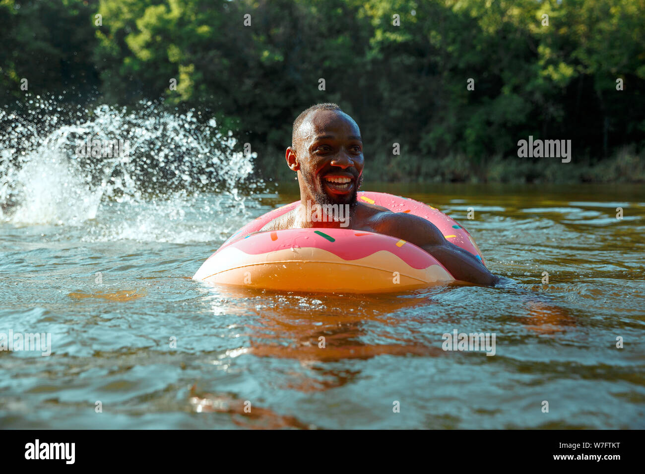 Happy man having fun while laughting and swimming in river. Joyful male ...