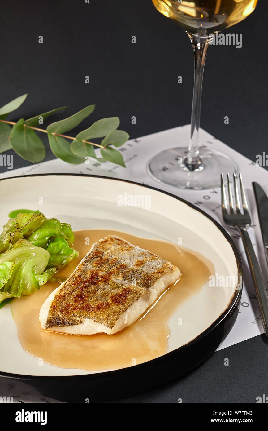 Delicious fish cooked in an oven and garnished with sauce and cabbage ...