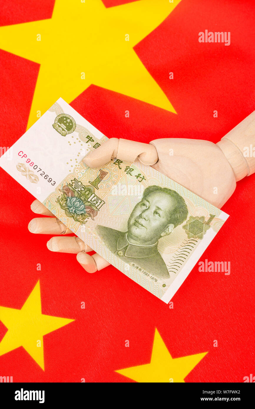 Chinese Yuan banknote in wooden manikin / mannequin hand with flag of ...