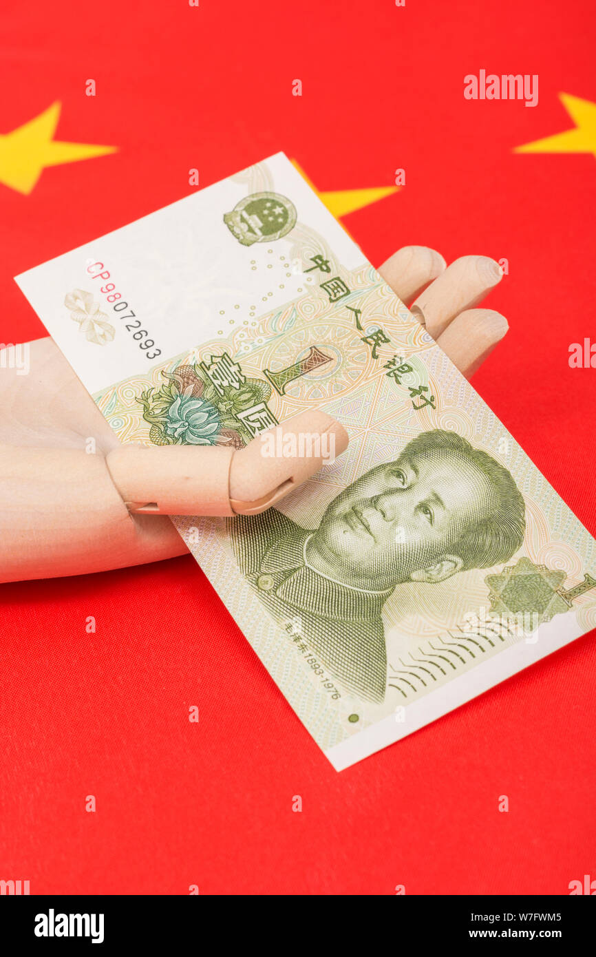 Chinese Yuan banknote in wooden manikin / mannequin hand with flag of ...