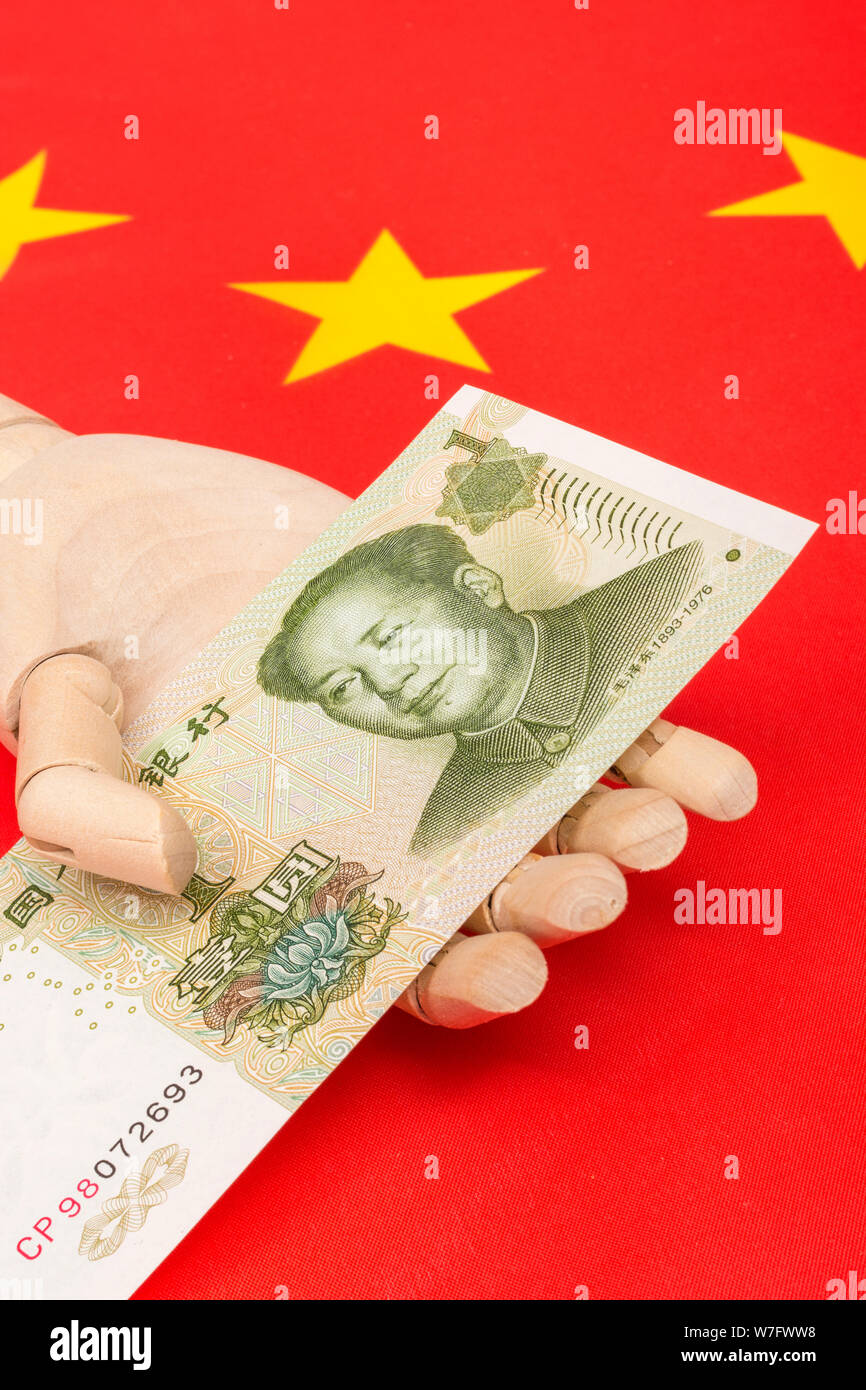 Chinese Yuan banknote in wooden manikin / mannequin hand with flag of ...