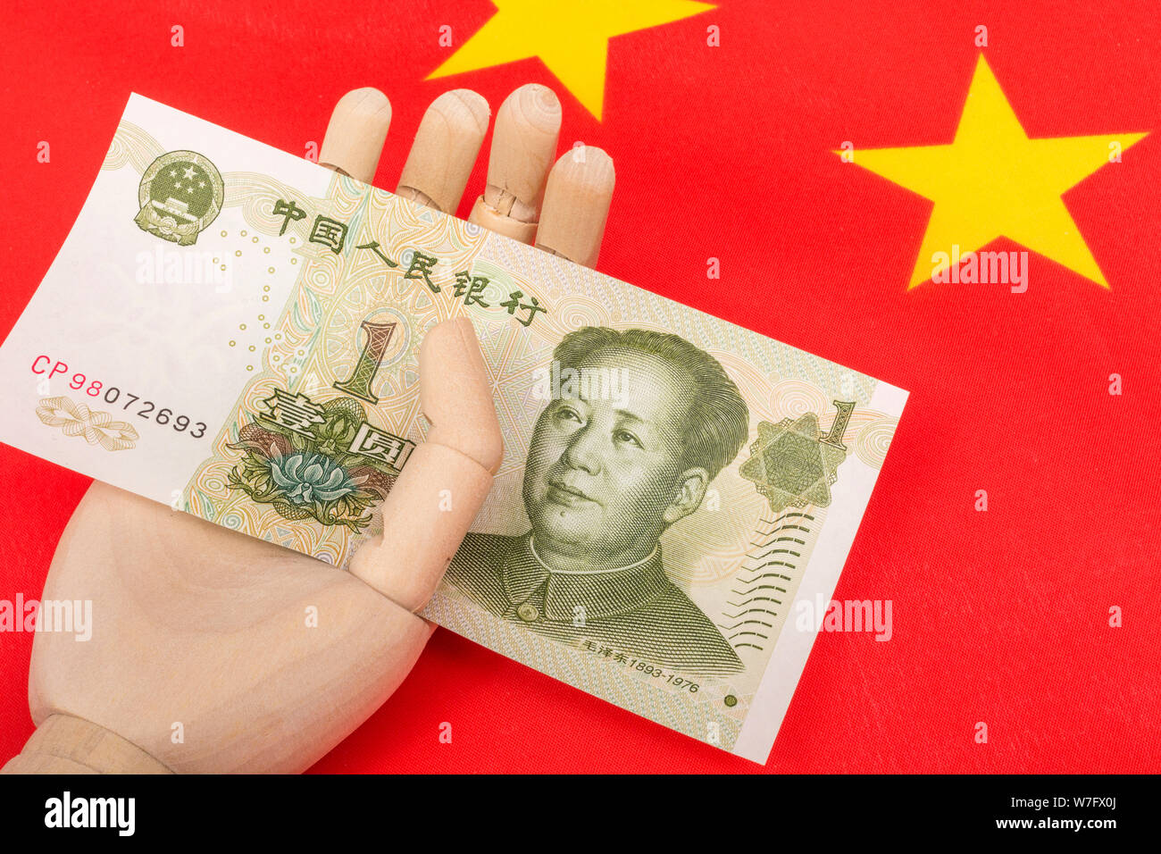 Chinese Yuan banknote in wooden manikin / mannequin hand with flag of ...
