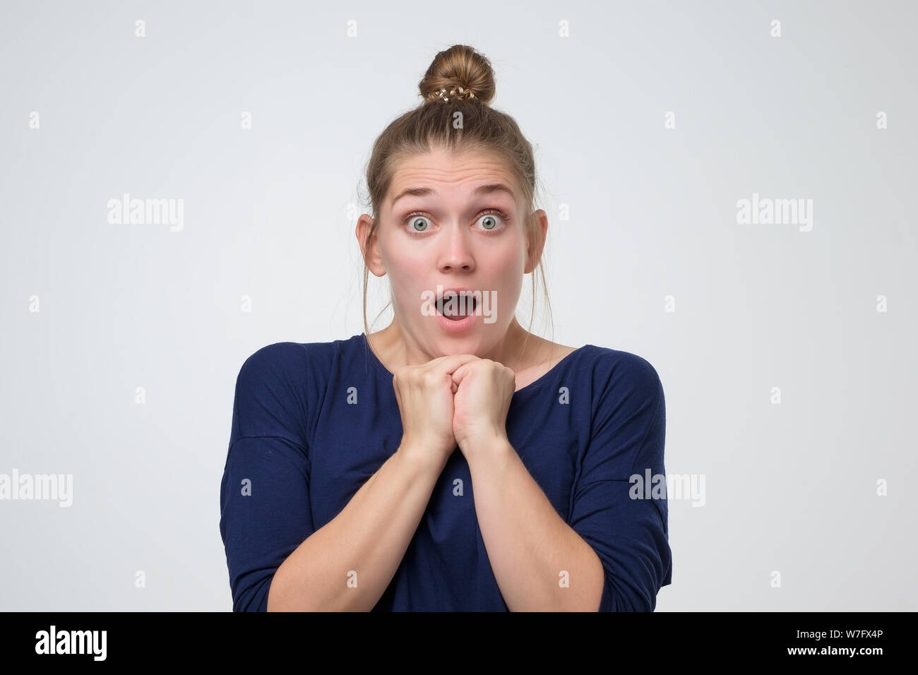 Wow concept. Beautiful surprised woman with hair bun standing with open ...