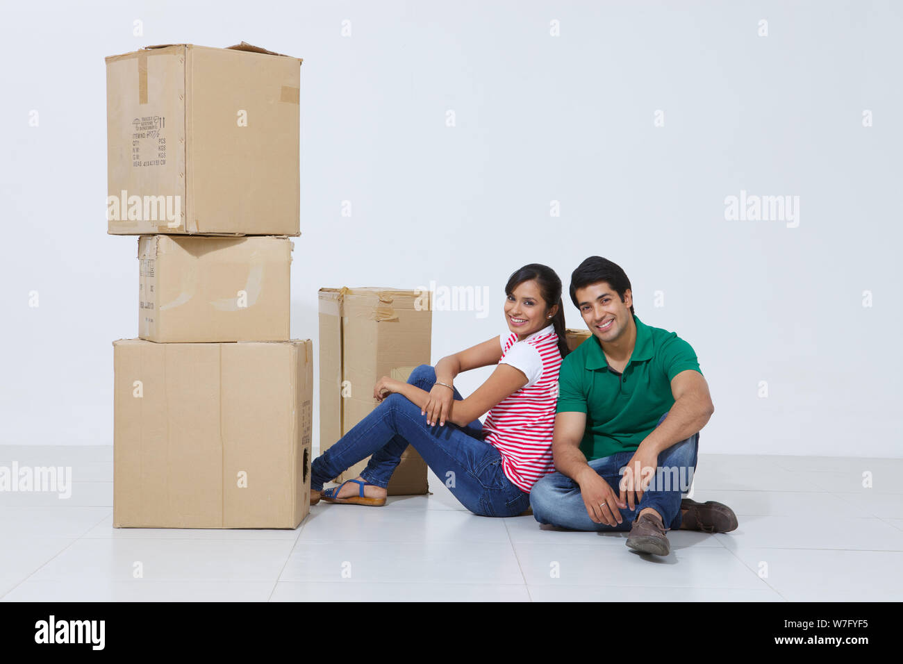 Couple sitting with cardboard boxes smiling Stock Photo - Alamy