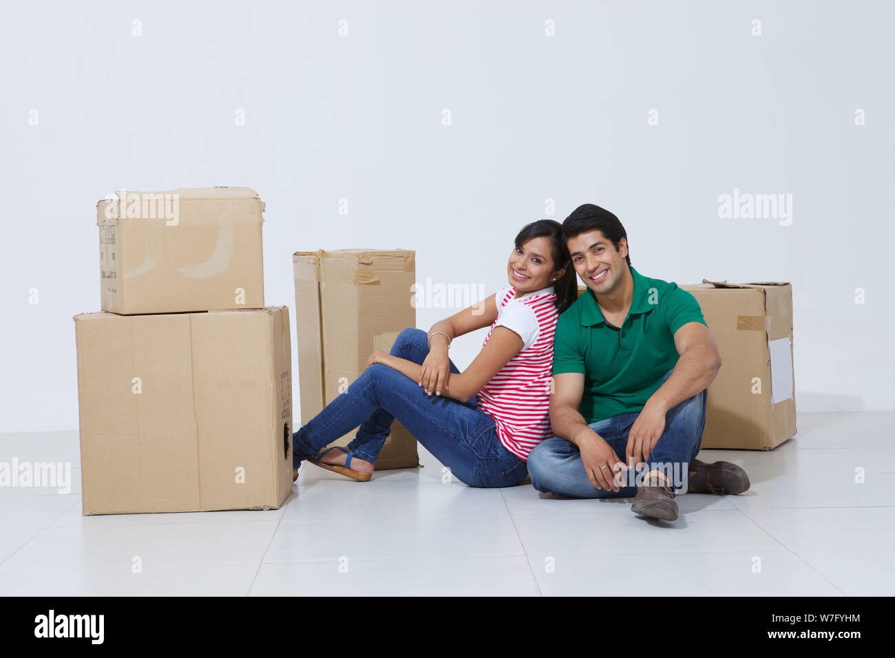 Couple sitting with cardboard boxes smiling Stock Photo - Alamy
