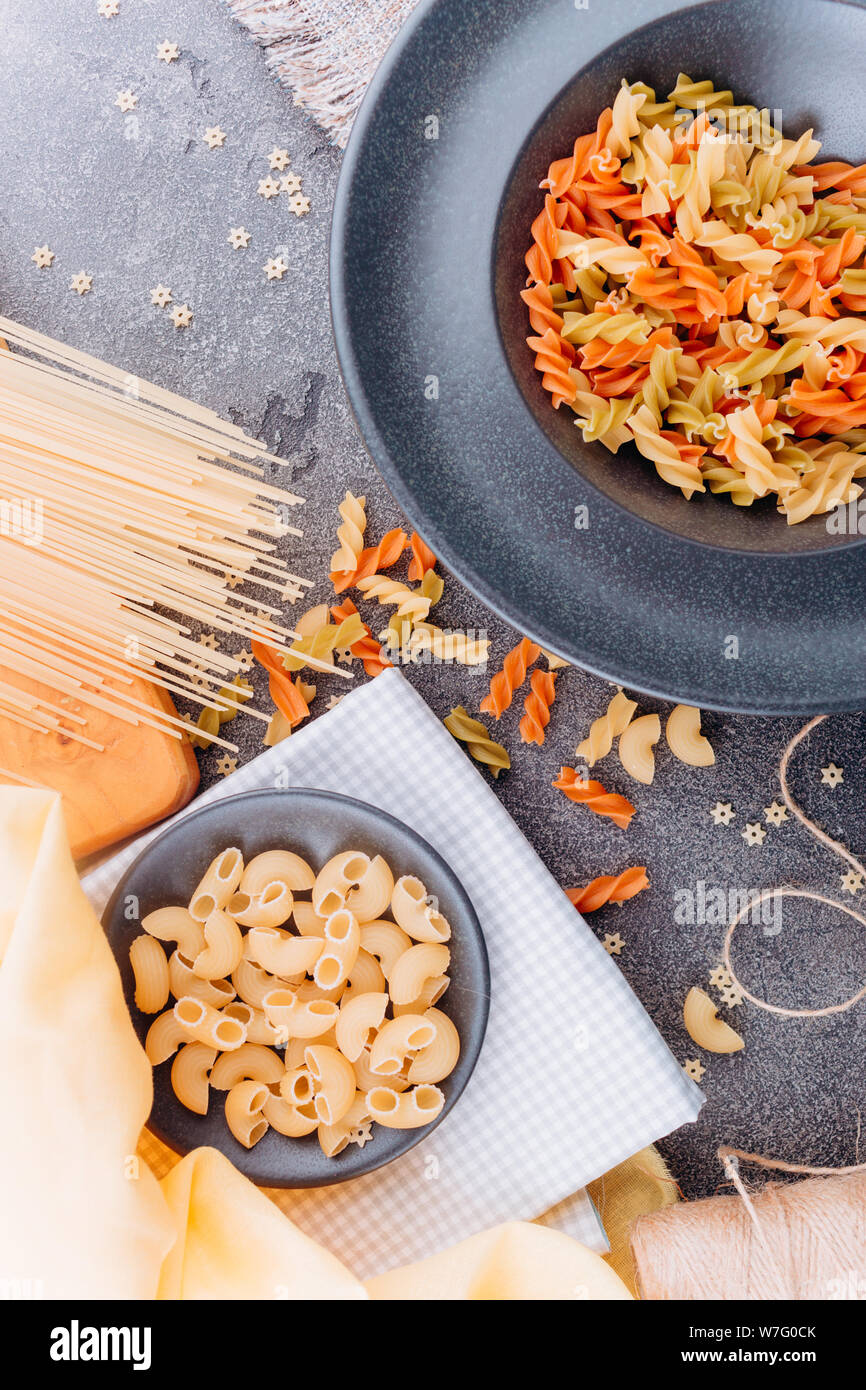 Different types of pasta on a black plate top view Stock Photo - Alamy