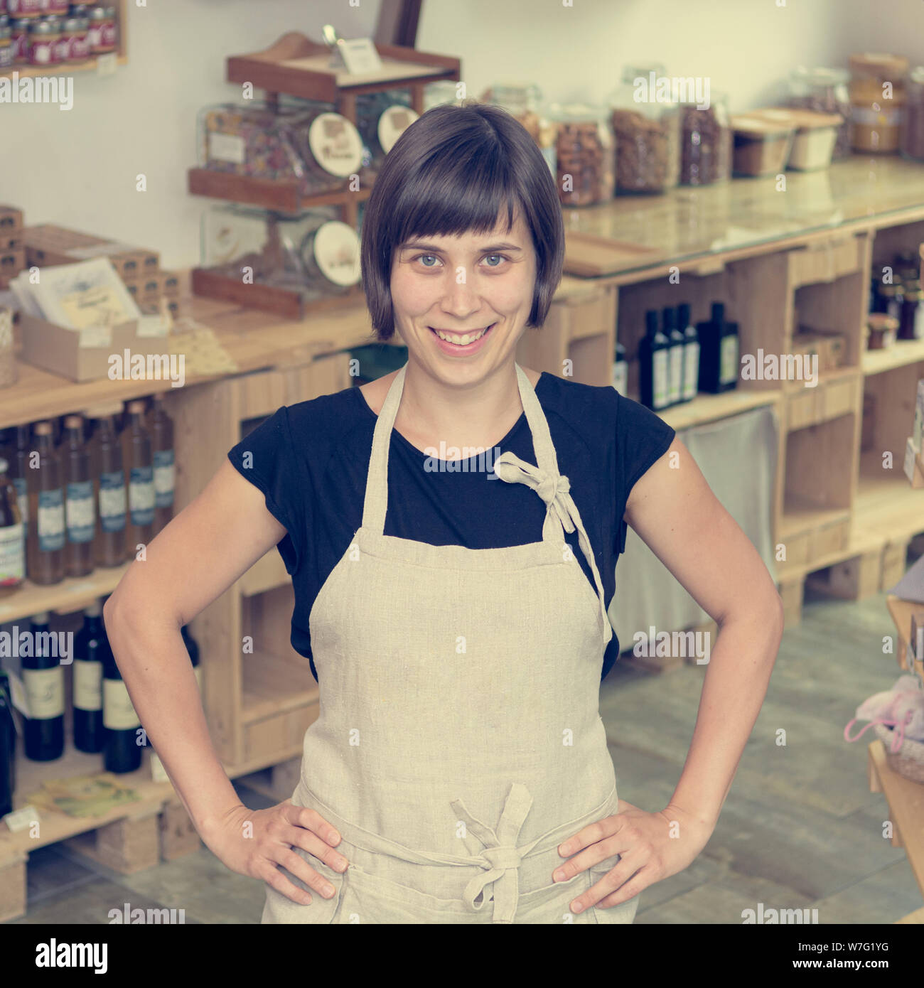Cherfull young female shop owner posing in front of shelves full of ...