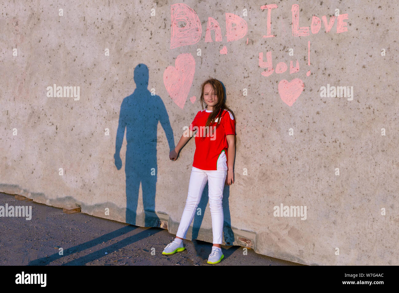 Happy dad holds daughter's hand. Shadow of dad and daughter on the wall ...