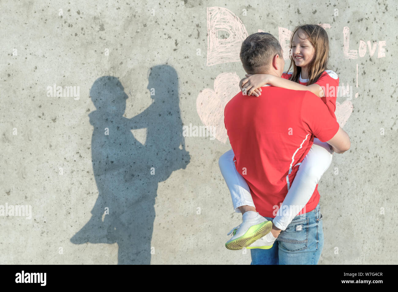 Happy Dad is holding a daughter. Shadow of dad and daughter on the wall ...