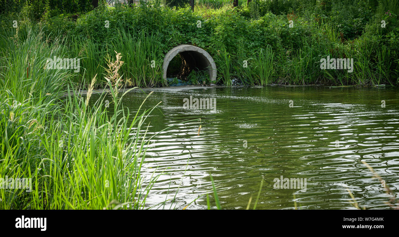 Pipe or tube for water sewer leading into the river Stock Photo - Alamy