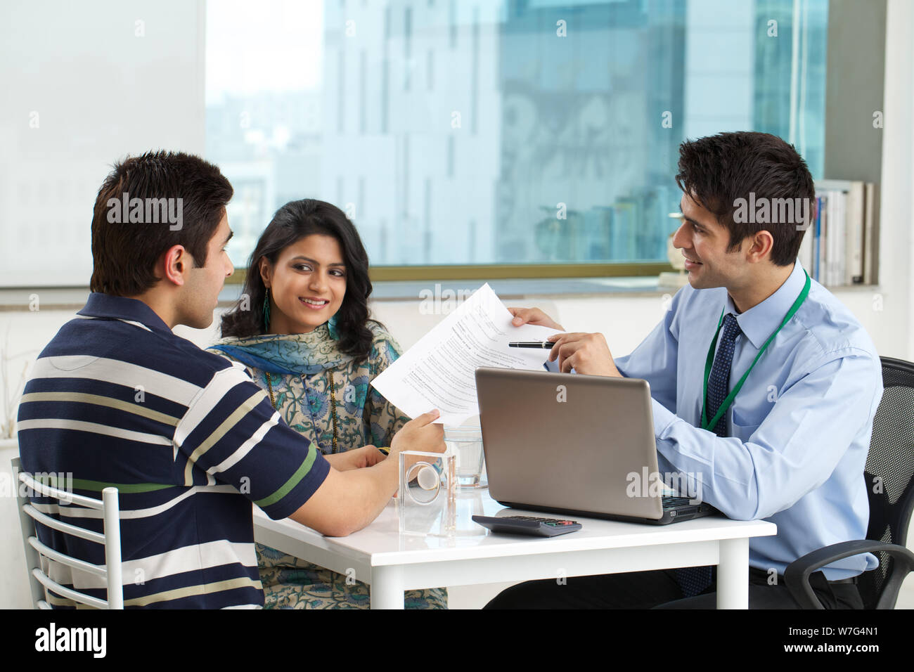 Executive explaining document to a couple Stock Photo - Alamy