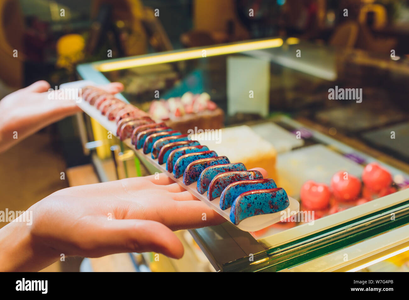 Close up of vendor's hands taking out cake from showcase in bakery ...